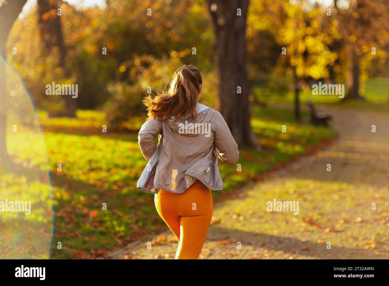 Hello autumn. Seen from behind modern woman in fitness clothes in the ...