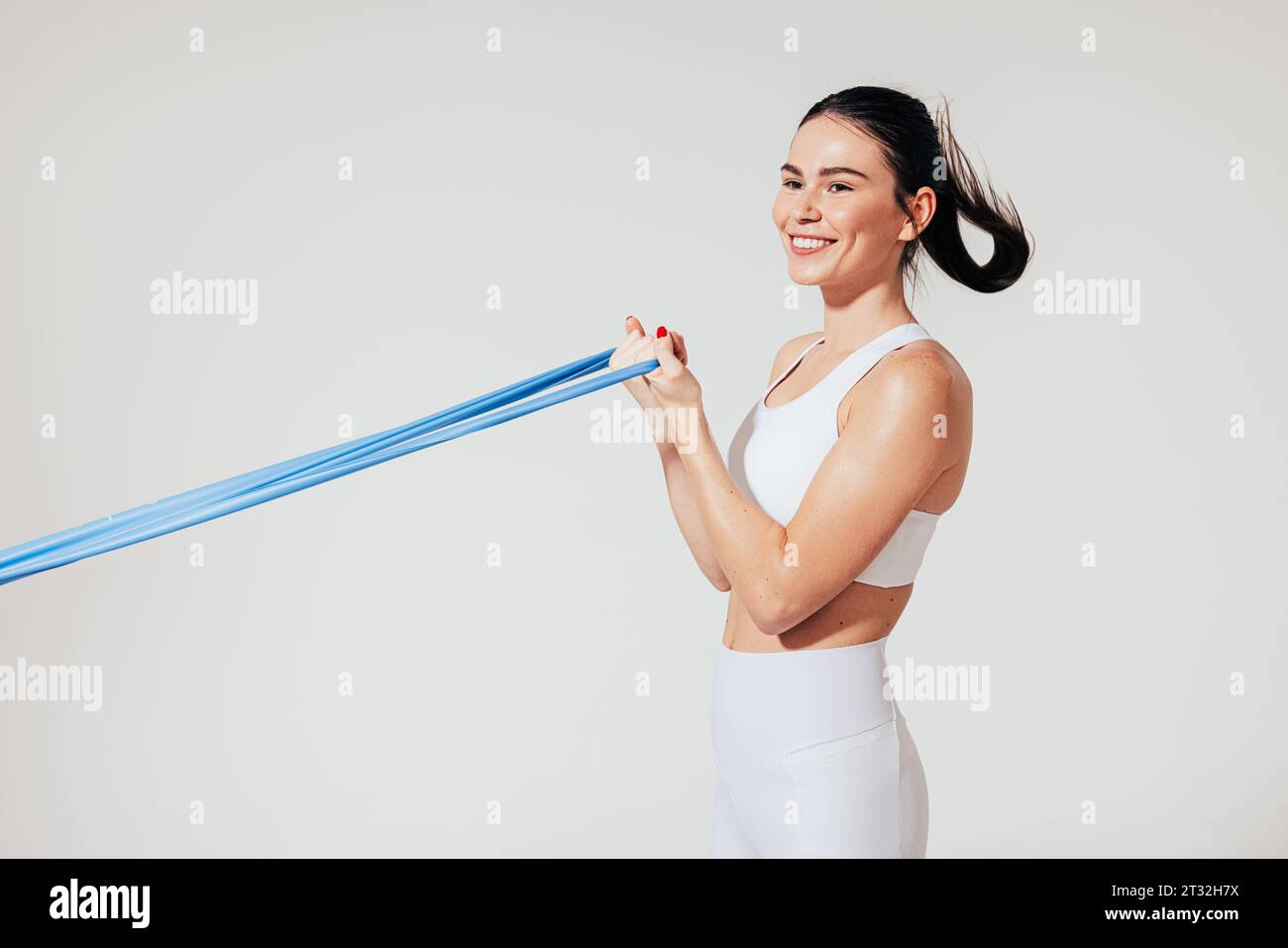 Side view of a young smiling female athlete flexing her hands using a resistance band Stock ...