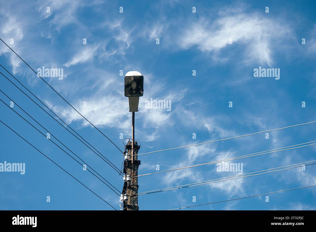 View of street lamp on concrete pole with wires against blue sky on ...