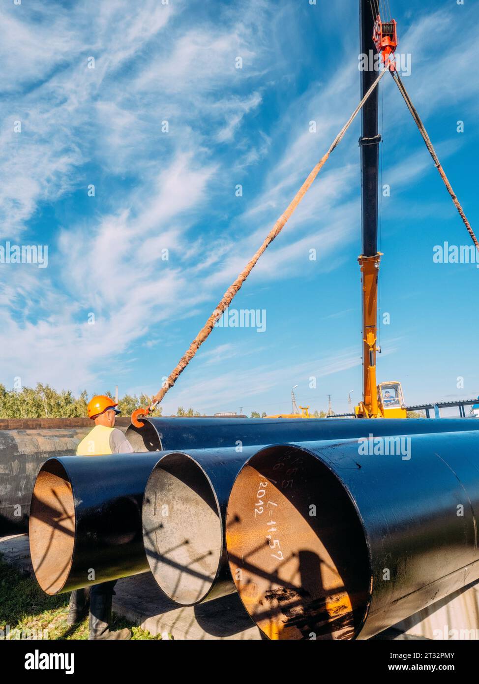 Slinger unloads large gasification pipes on summer day. Pipes for ...