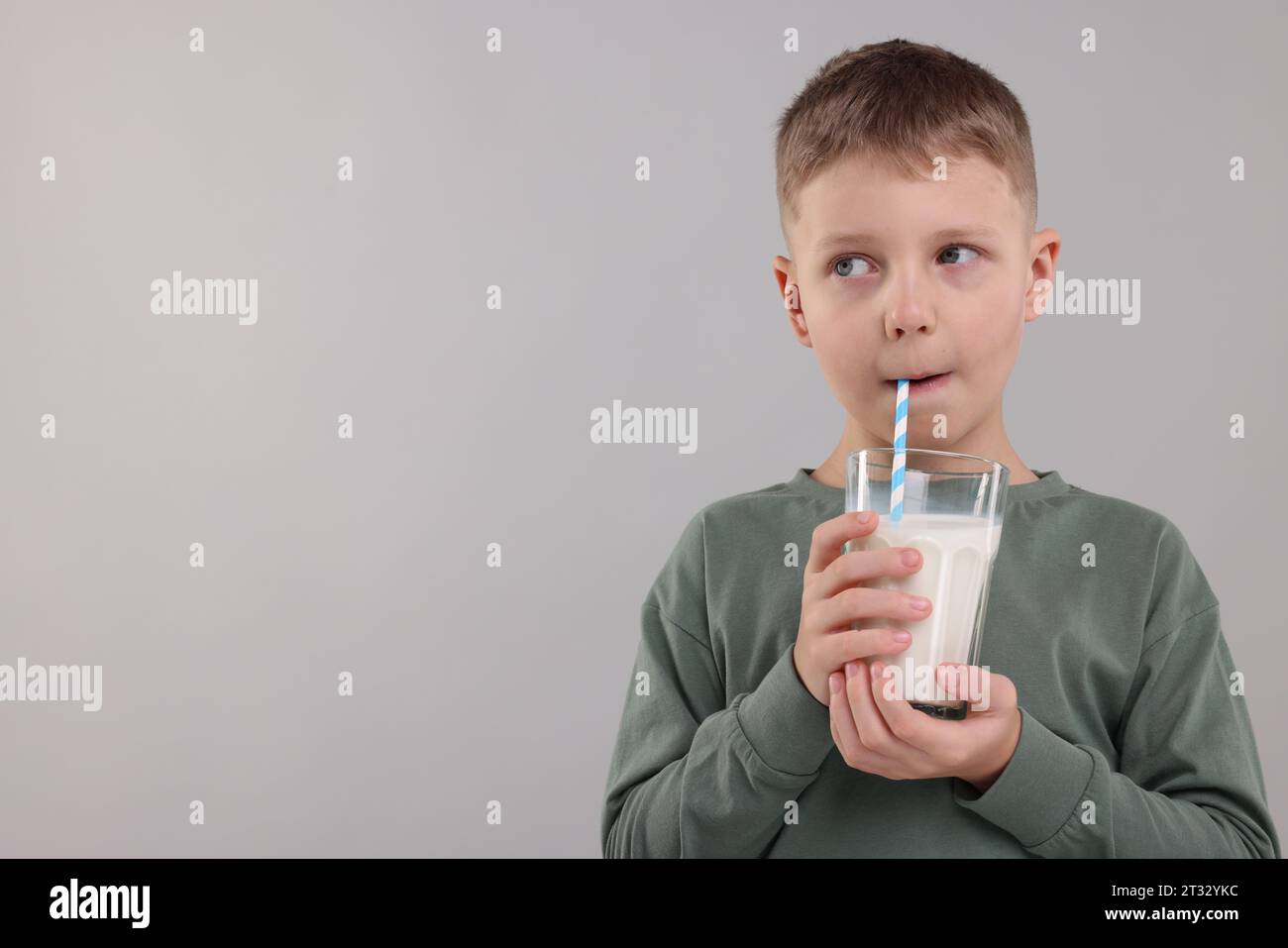 Cute boy drinking fresh milk from glass on light grey background, space ...