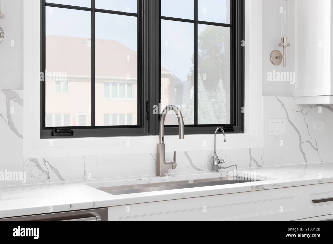 A luxury kitchen faucet detail with white cabinets, white marble ...
