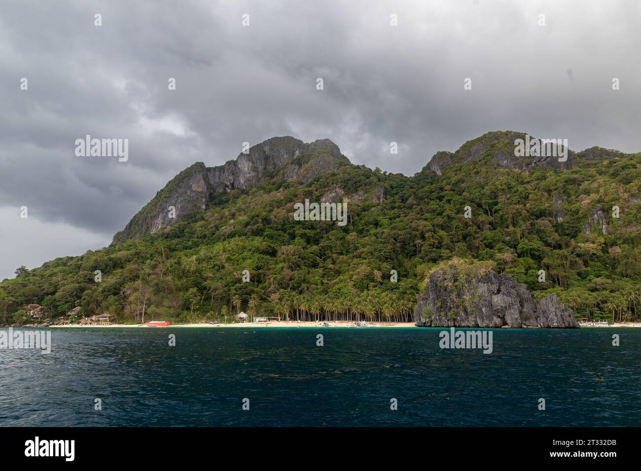Secluded beach at the base of limestone karst formations rising out of ...