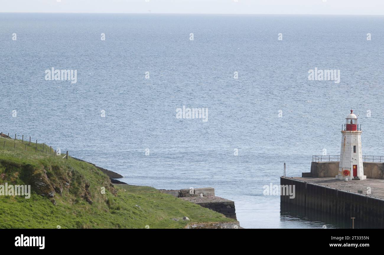 An aerial view of a tall white lighthouse with the sea in the ...