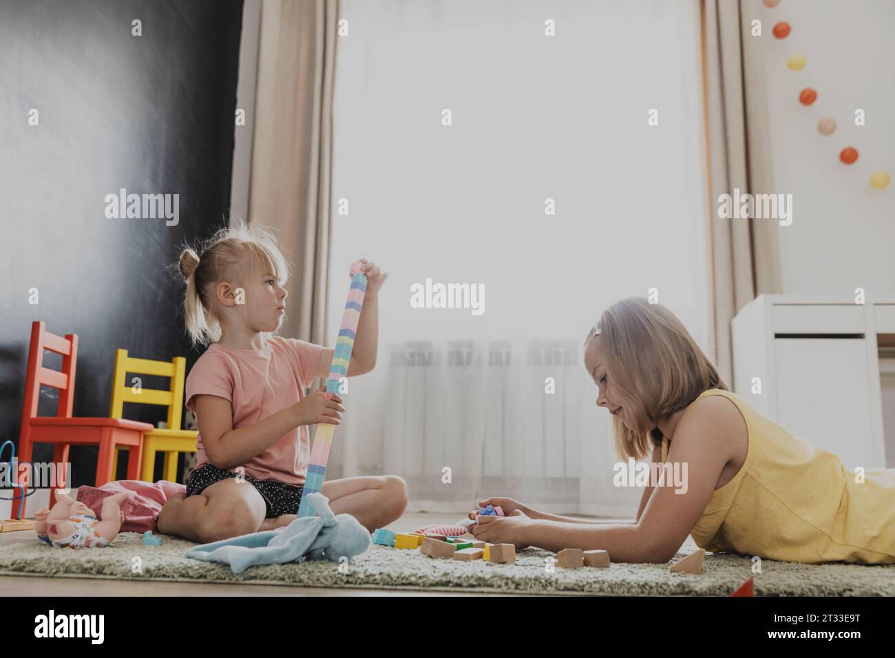Children playing with colorful toys. Kids sitting on carpet at home ...