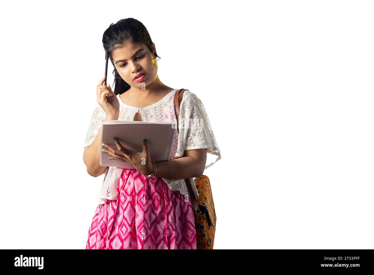 A pretty young Indian girl thinking while taking notes and scratching ...