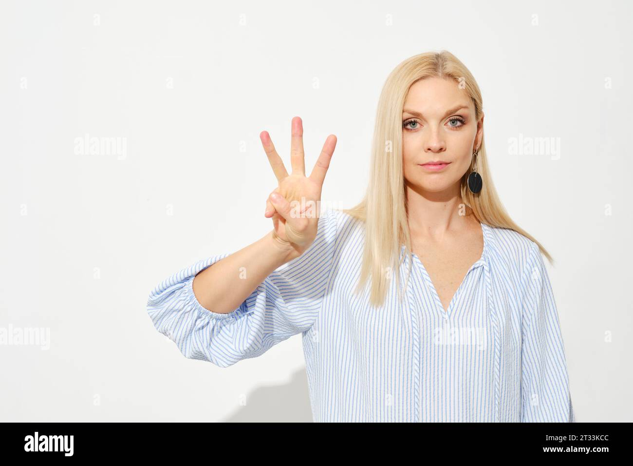 Attractive blonde woman shows three fingers. Counting with fingers ...