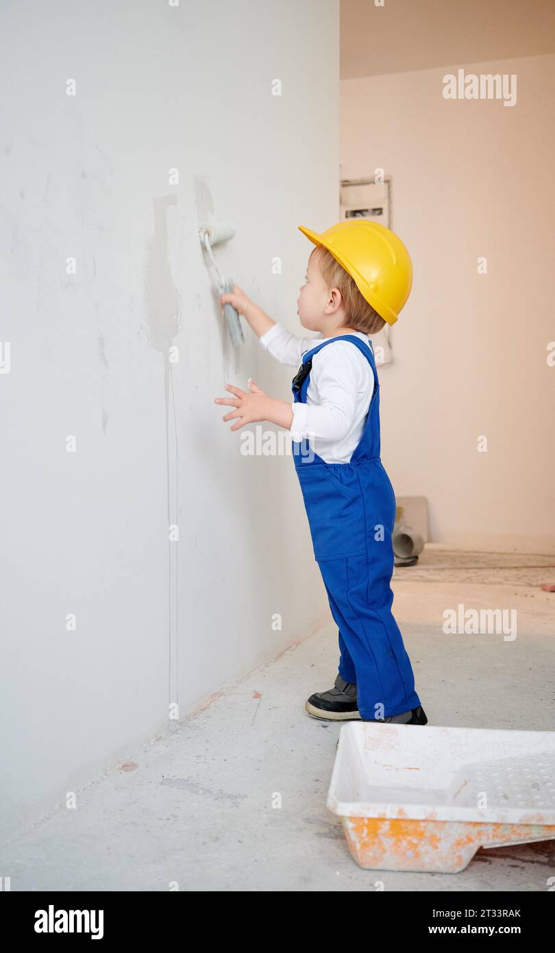 Full length of child construction worker painting wall in apartment ...