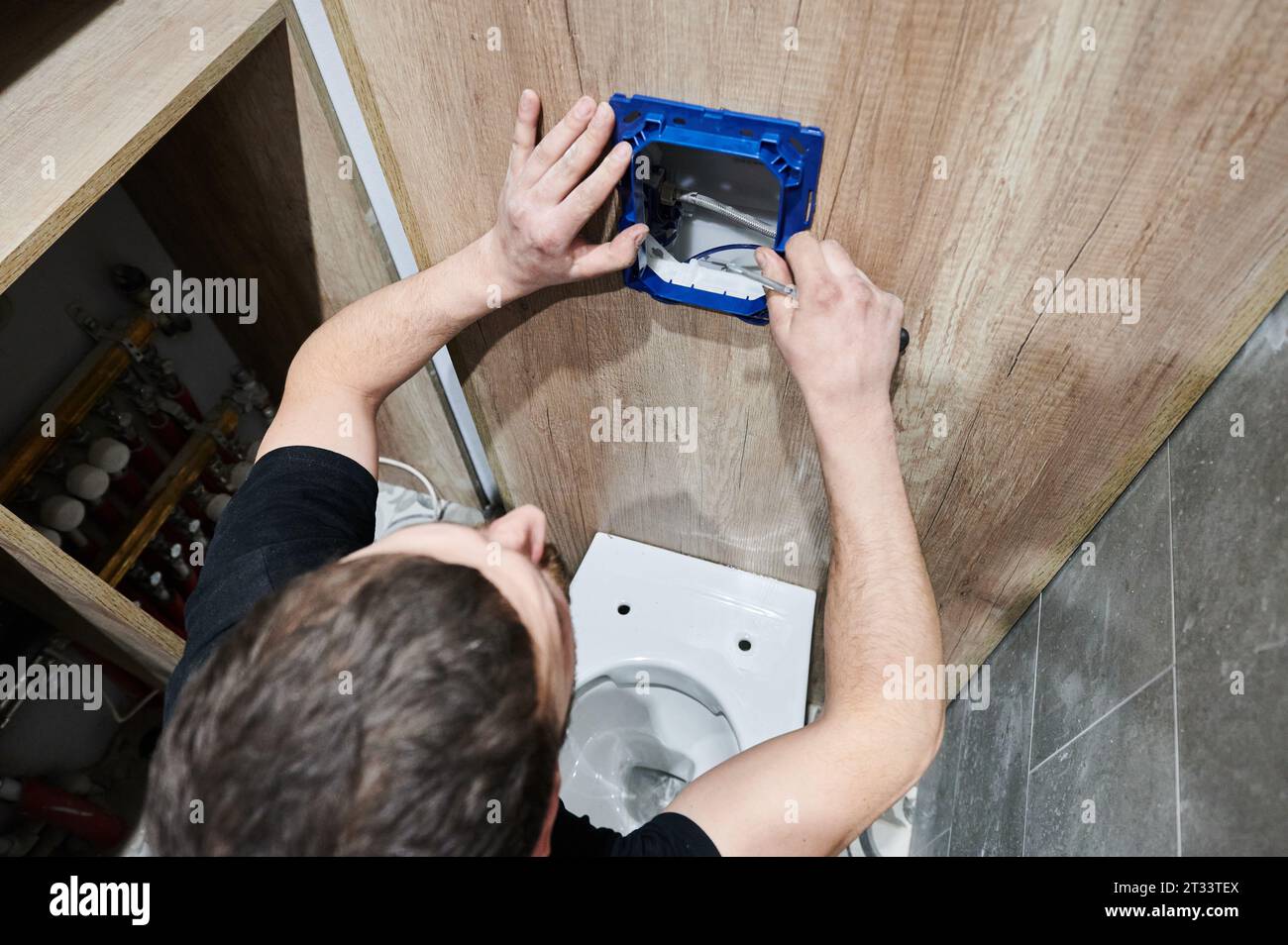 Male worker holding screwdriver tool while installing toilet flush ...