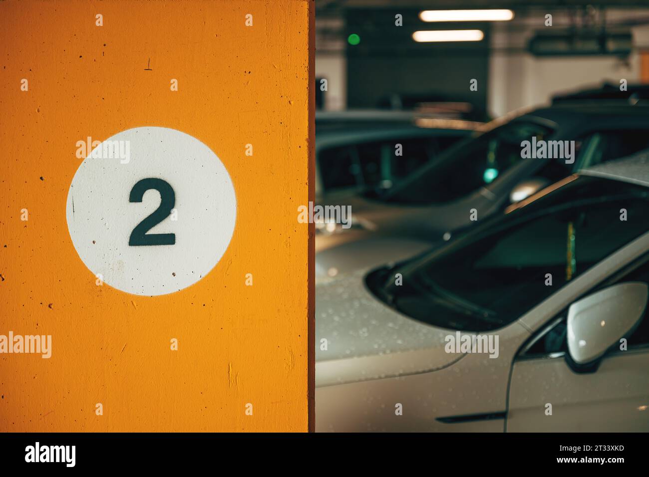 Number 2 on underground parking garage wall with cars in background ...