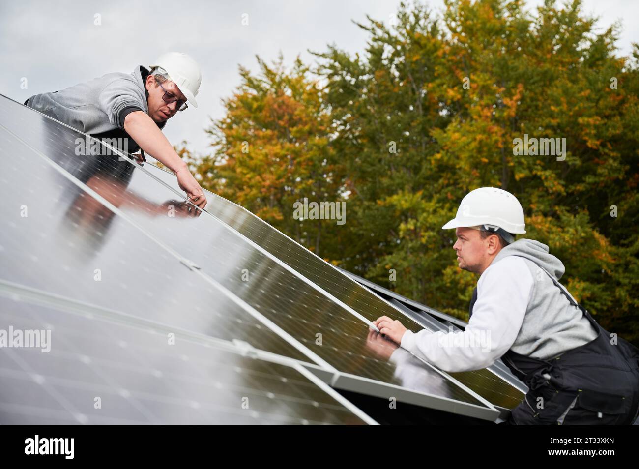 Technicians building photovoltaic solar module station on roof of house ...