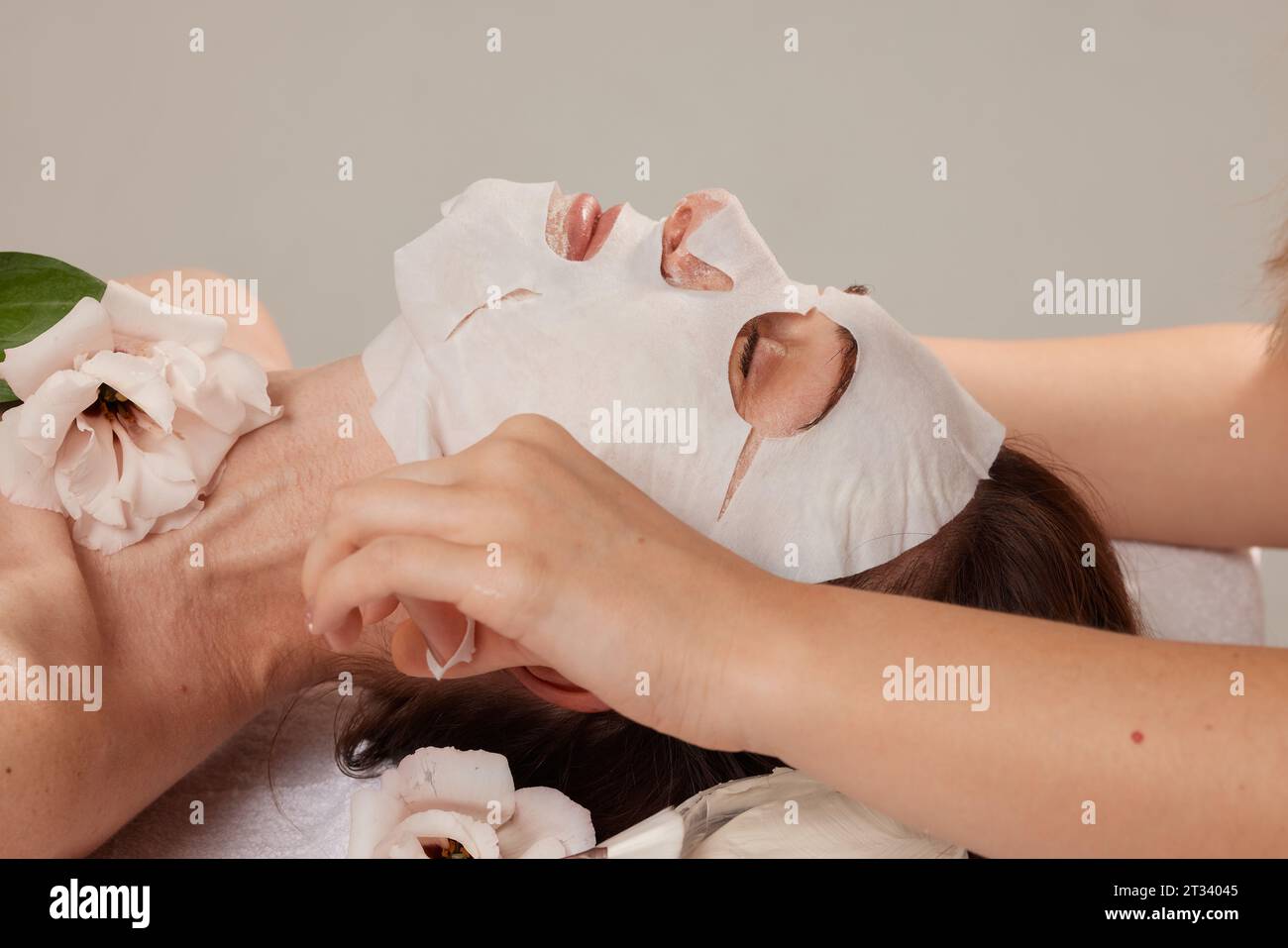 Beautician smoothes sheet mask on woman face for rehydrate face skin ...