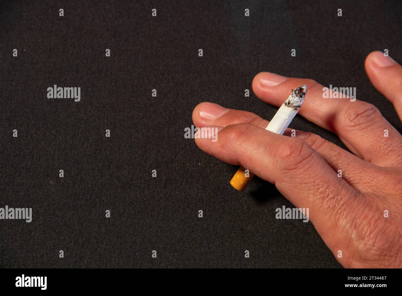 Hand of a European adult man holding a lit cigarette with his fingers ...
