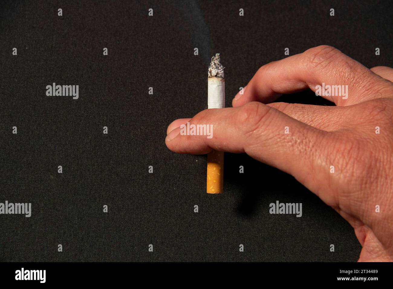 Hand of a European adult man holding a lit cigarette with his fingers ...