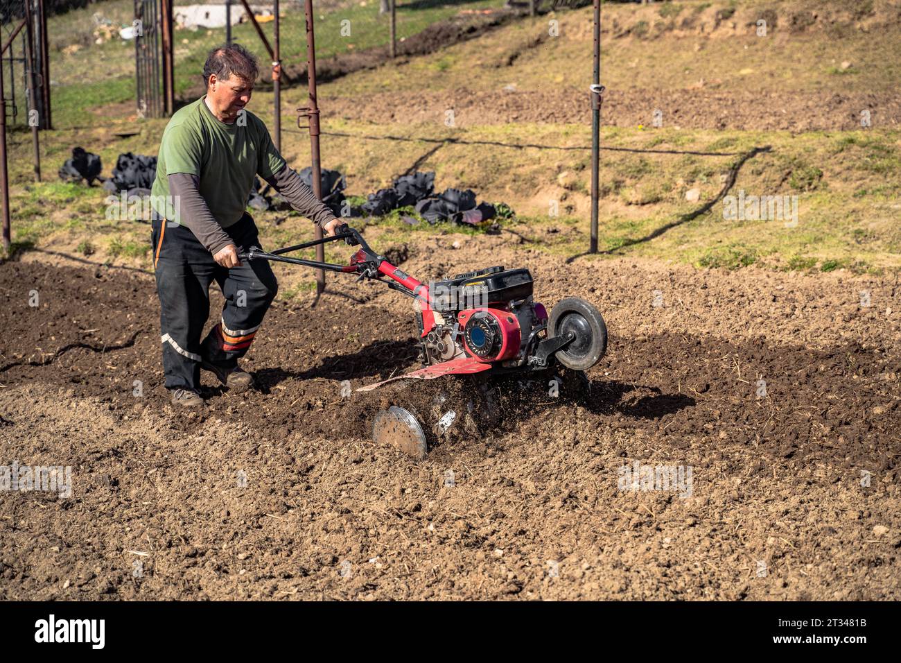 A farmer man plows the land with a cultivator. Machinery cultivator for ...