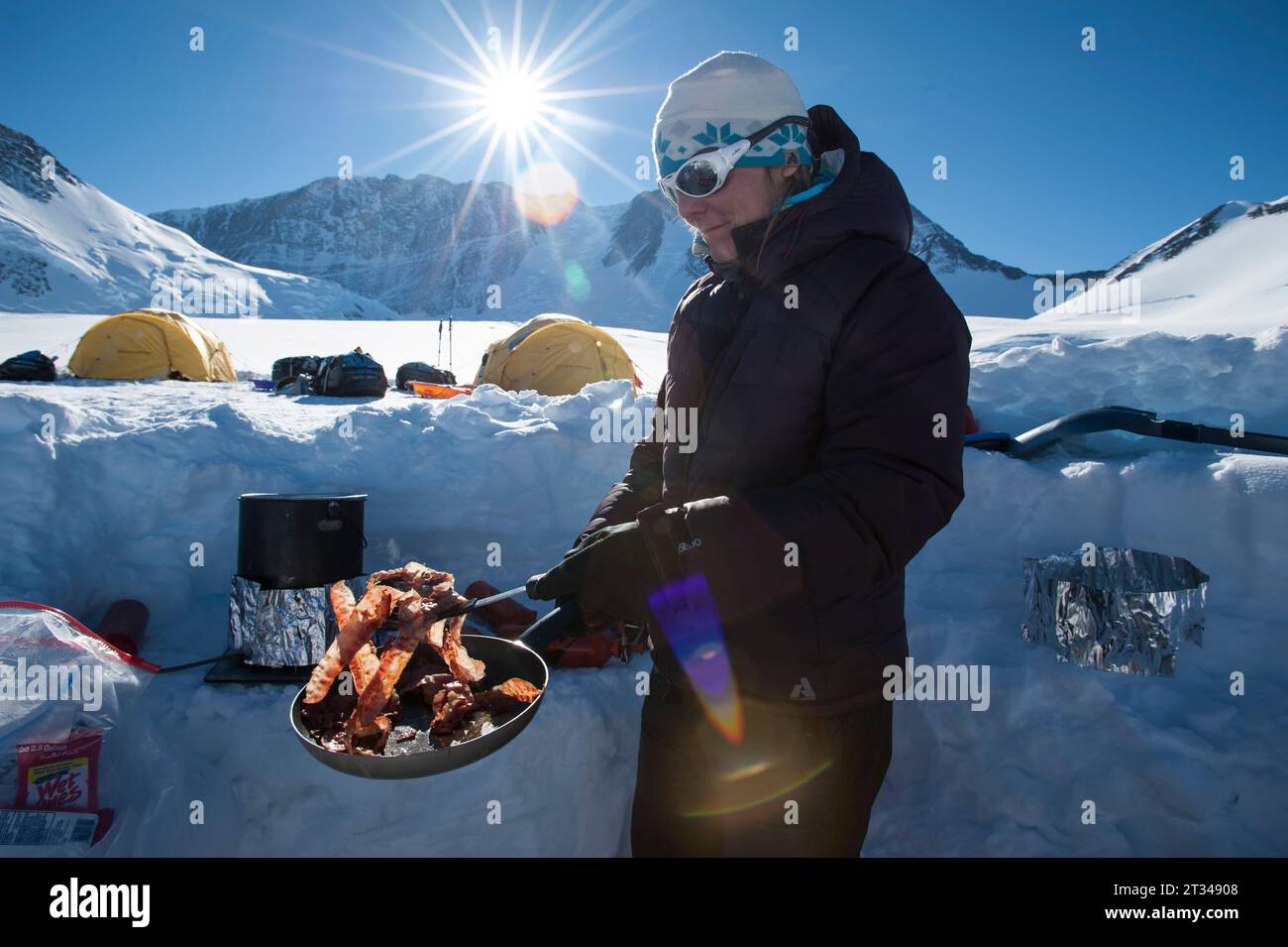Female climber cooking bacon in Antarctica Stock Photo - Alamy