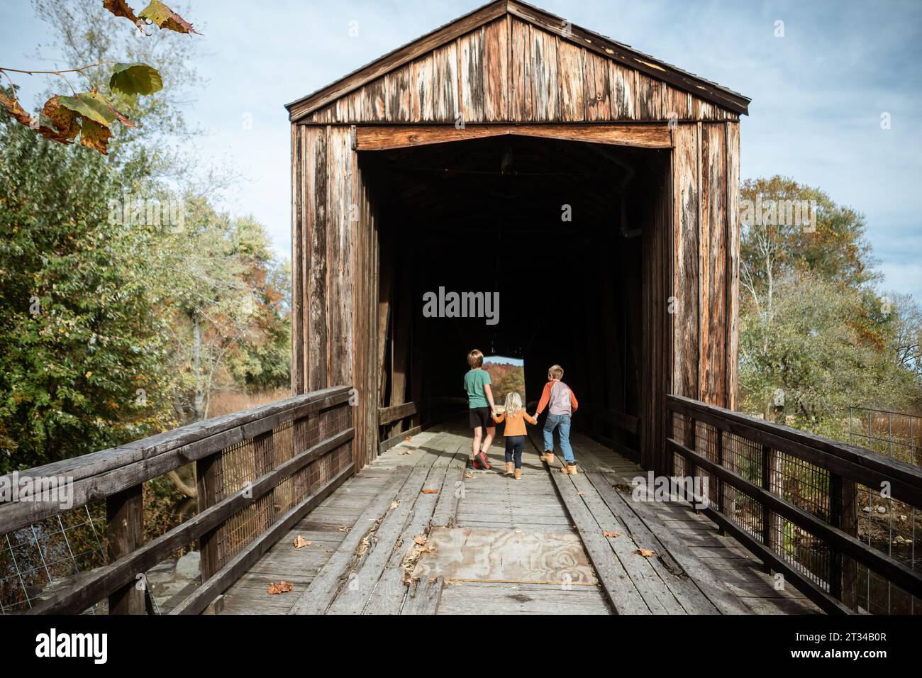 Children holding hands walking under a historic covered bridge i Stock ...