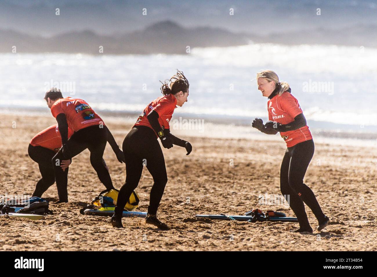 People playing a game to warm up during a surfing lesson on Fistral ...