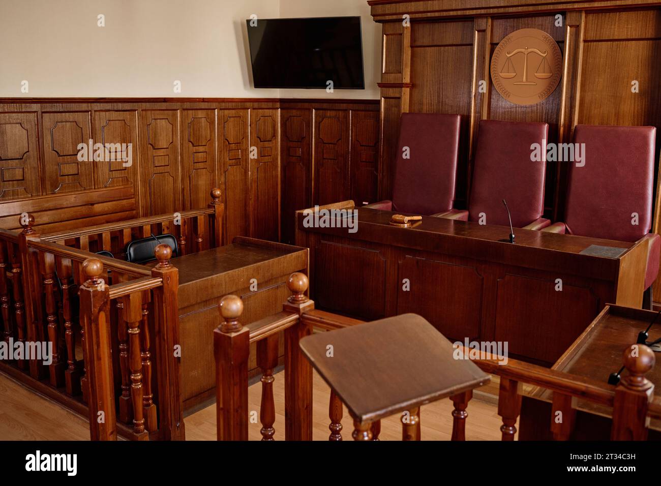 Corner of spacious courtroom with screen, wooden desks and railings and ...