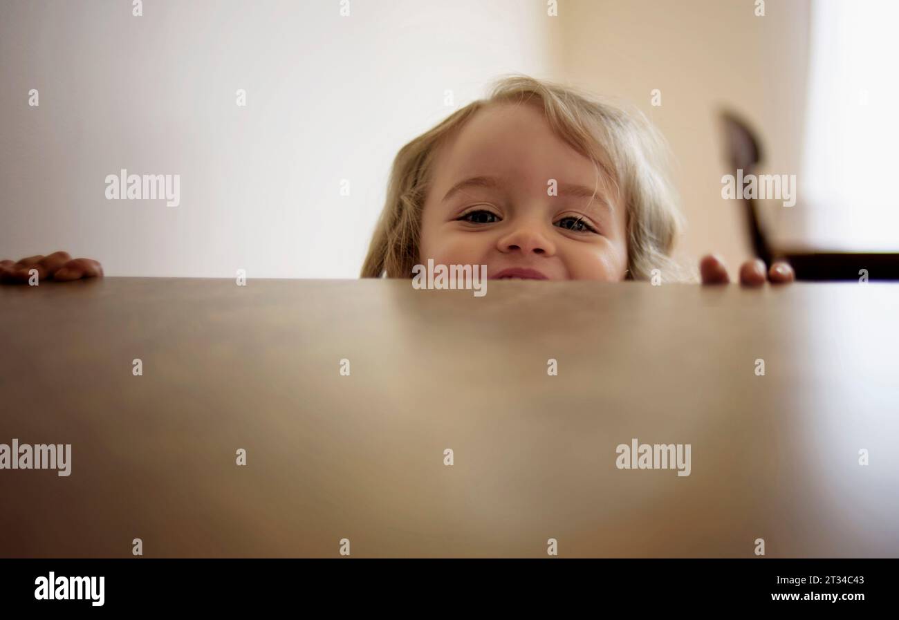 Happy little girl peeking over countertop in kitchen Stock Photo - Alamy