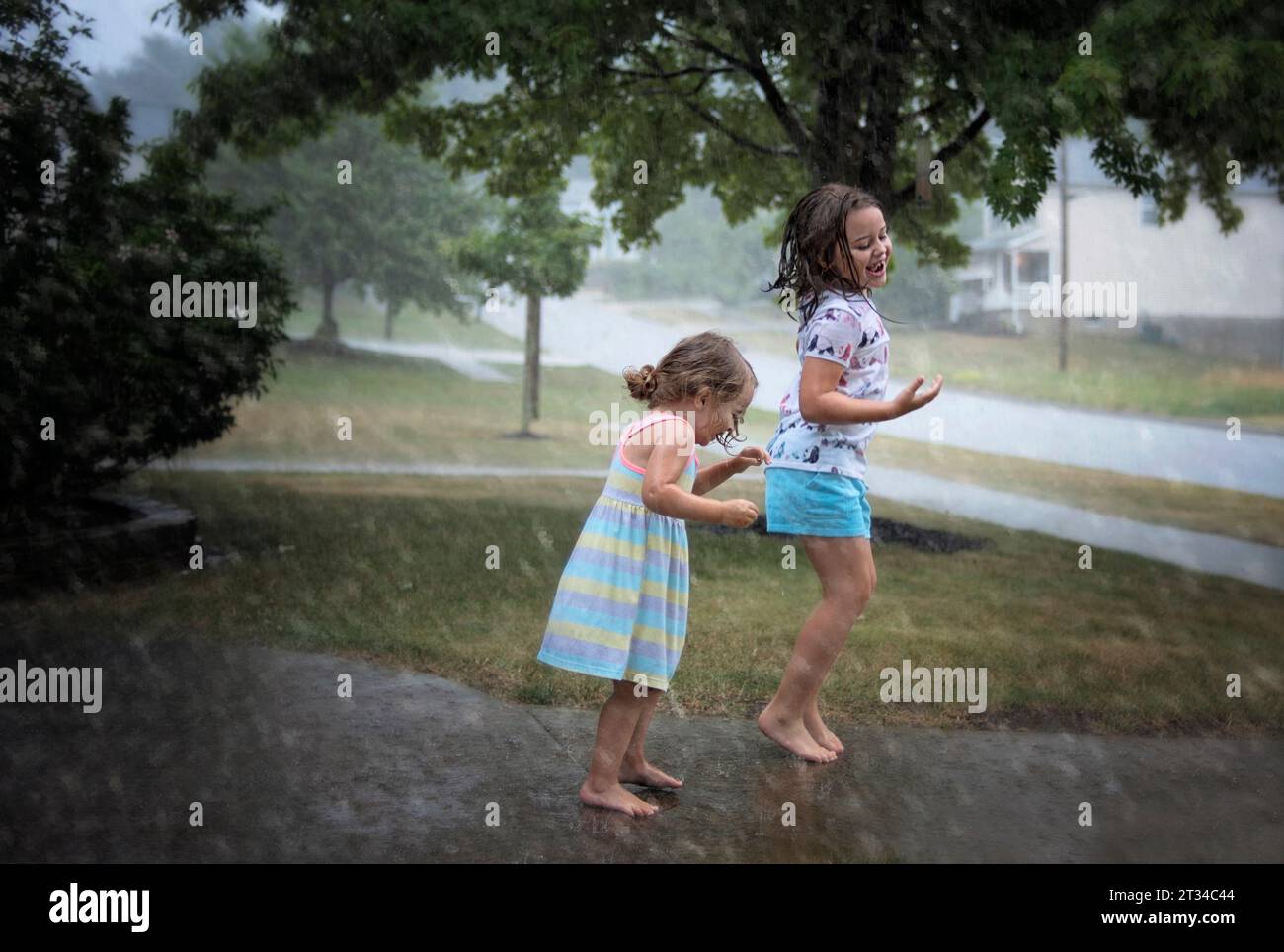 Sisters jumping in puddles during summer rain Stock Photo - Alamy