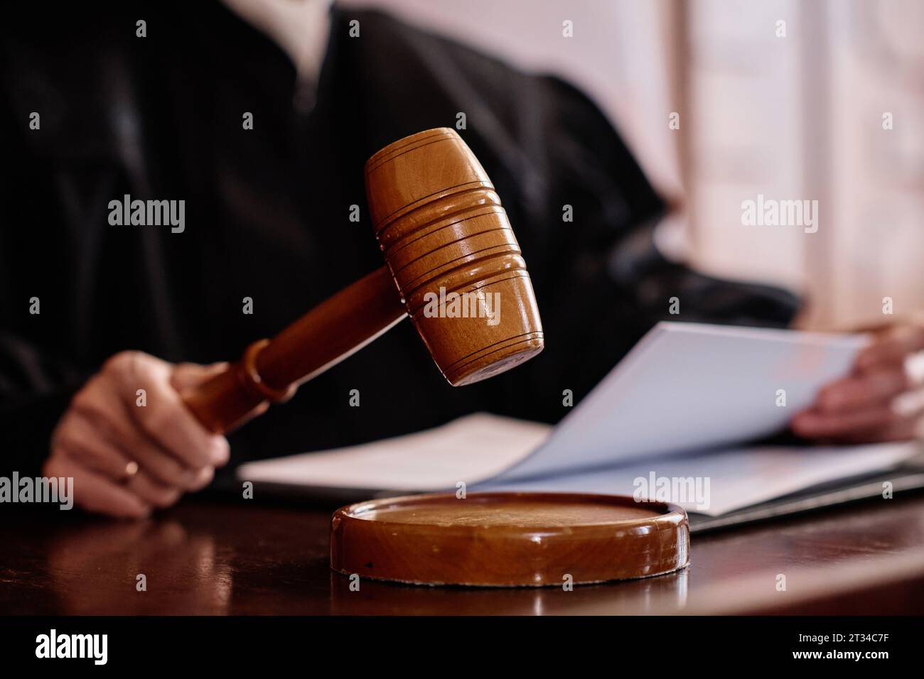 Wooden gavel held by experienced female judge over sounding block on ...