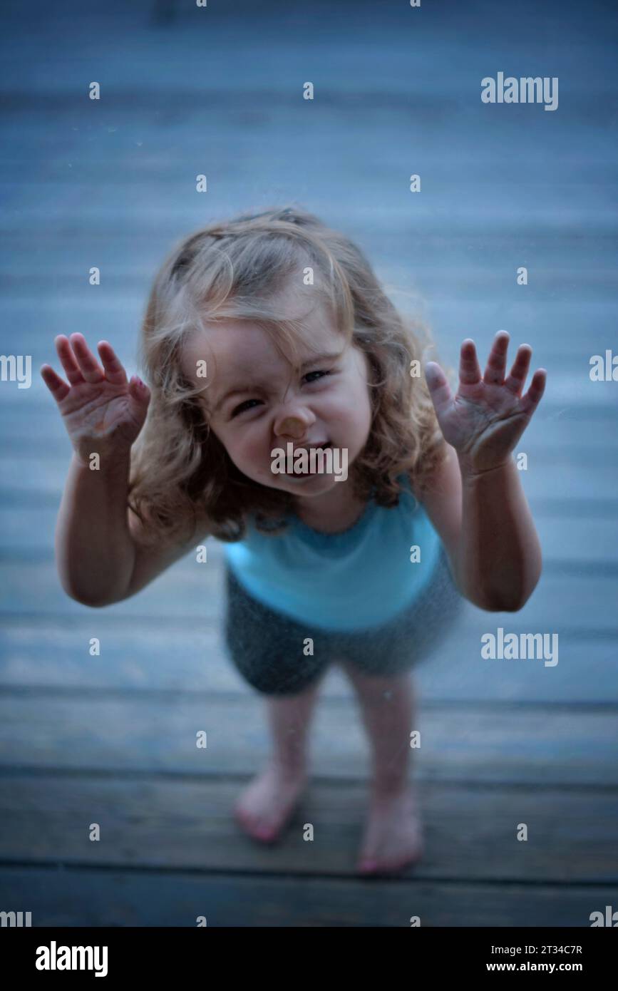 Little girl looking through window with face smashed on glass Stock ...