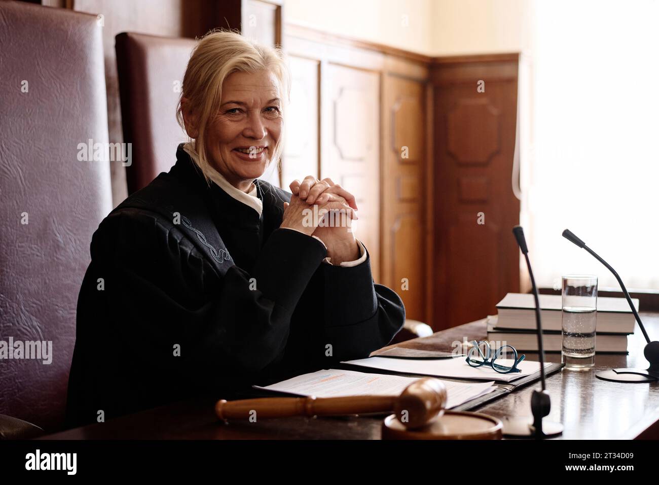 Mature successful blond judge wearing black mantle looking at camera ...