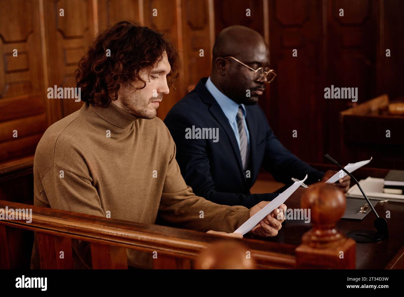 Young male suspect and his attorney looking through juridical documents ...
