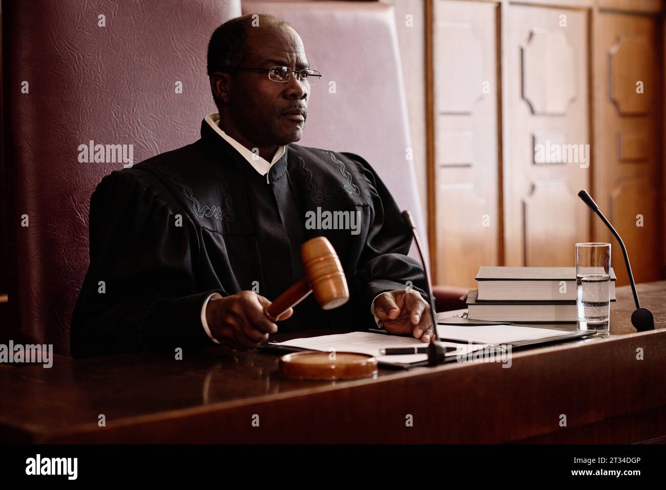Experienced male judge with wooden gavel over sounding block sitting by ...