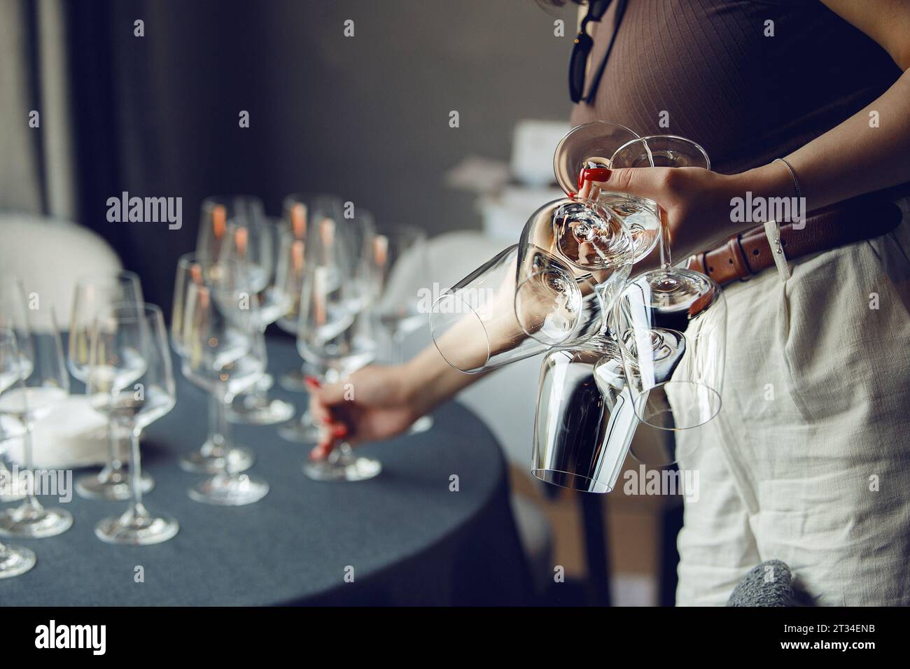 Woman waiter takes few empty wine glasses from bar table, close up ...
