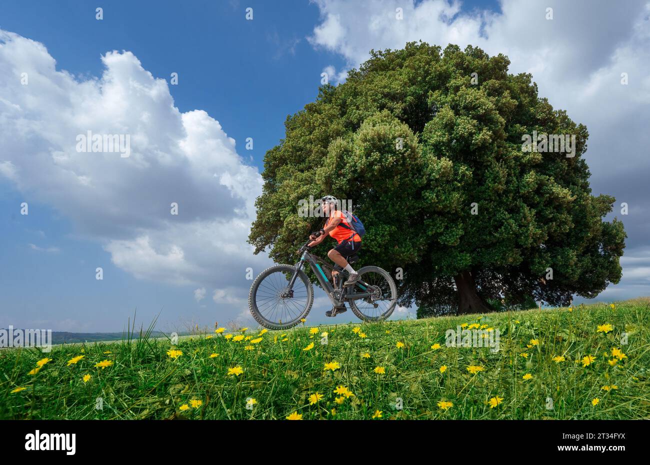 nice senior woman riding her electric mountain bike below a huge stone ...