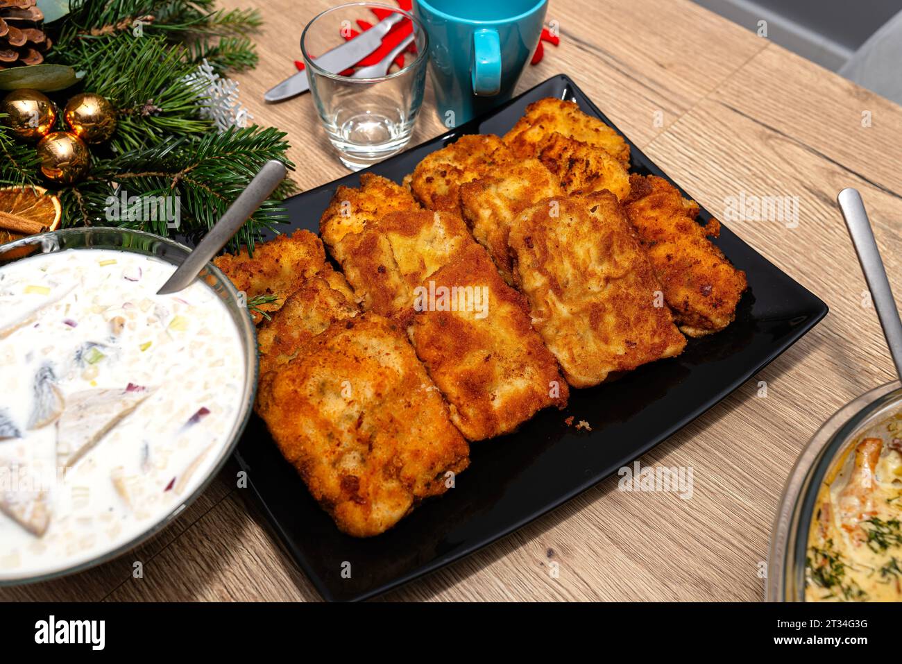 Fried fish fillets and herrings in cream on the Christmas table during ...