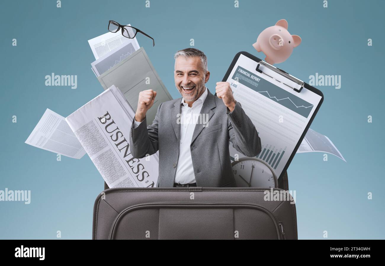 Cheerful businessman celebrating with arms raised and office items in a ...
