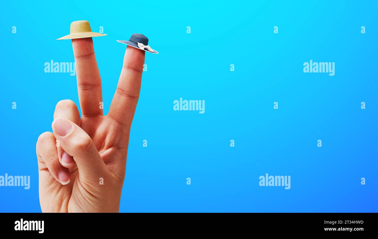 Female hand making a V sign and wearing tiny beach hats on two fingers ...