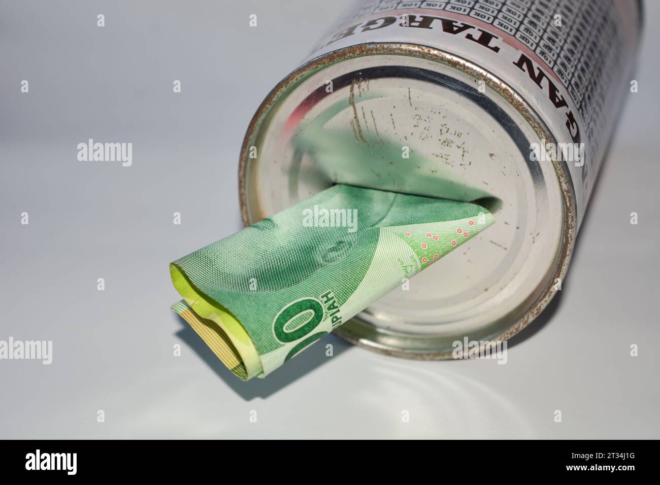 Hand putting Indonesian rupiah money into traditional Indonesian white ...