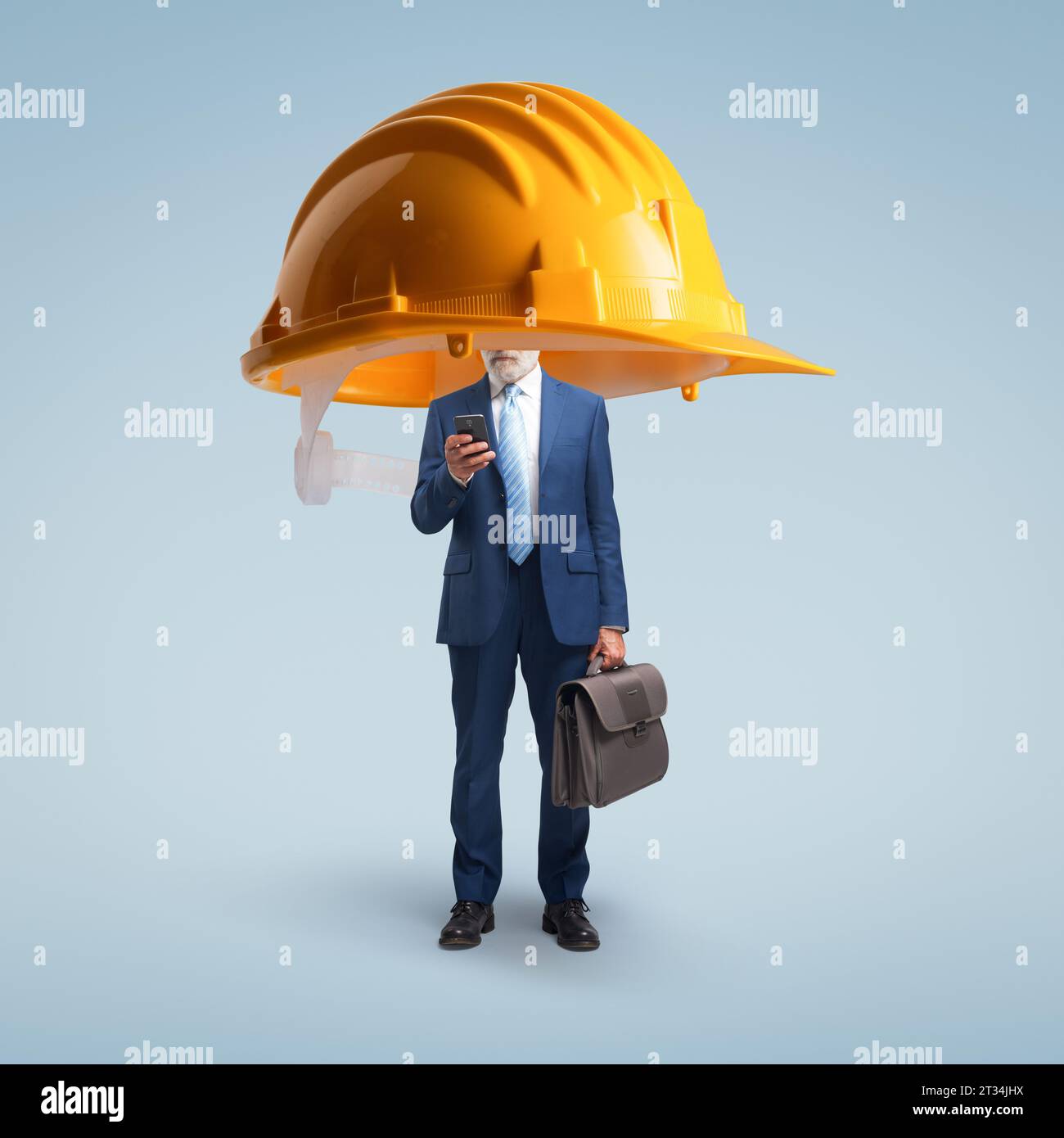 Big safety helmet protecting a corporate businessman using a smartphone ...