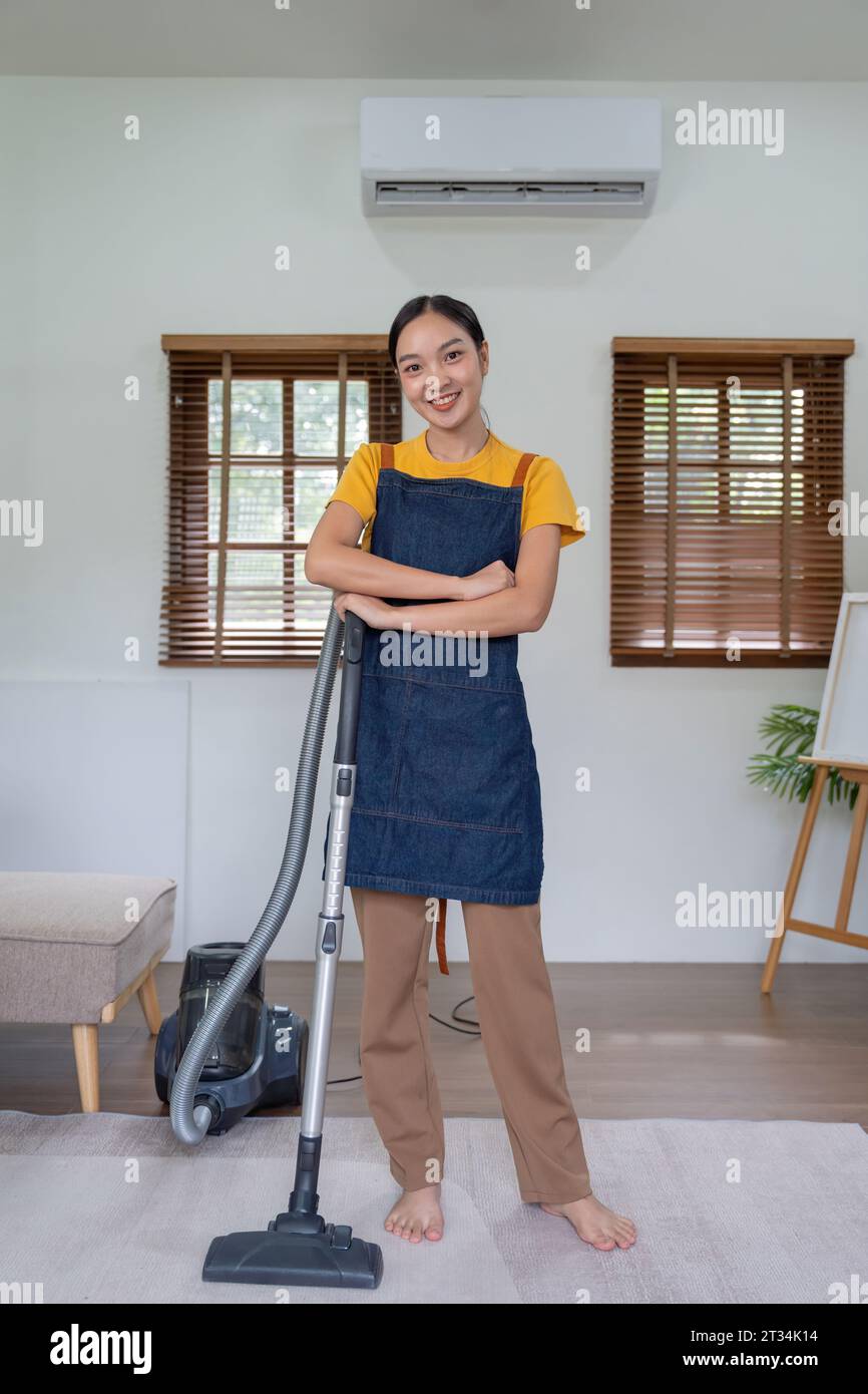 Asian Lady Doing House Chores In Apron Young Housewife Using Vacuum