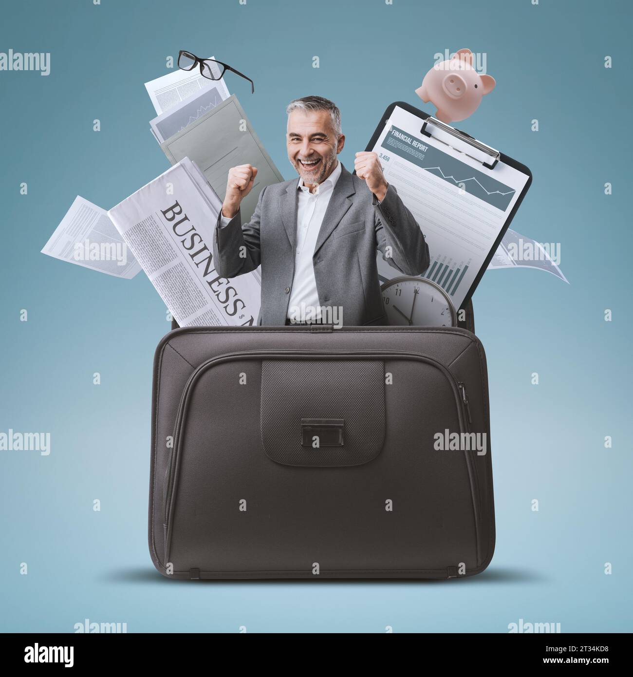 Cheerful businessman celebrating with arms raised and office items in a ...
