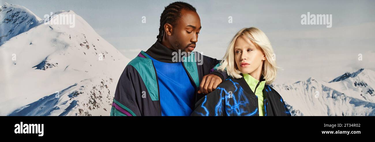 stylish multicultural couple in bold clothes with snowy mountain on ...