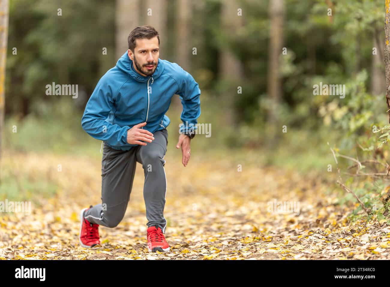 A young athlete is warming up before running training in the park. It ...
