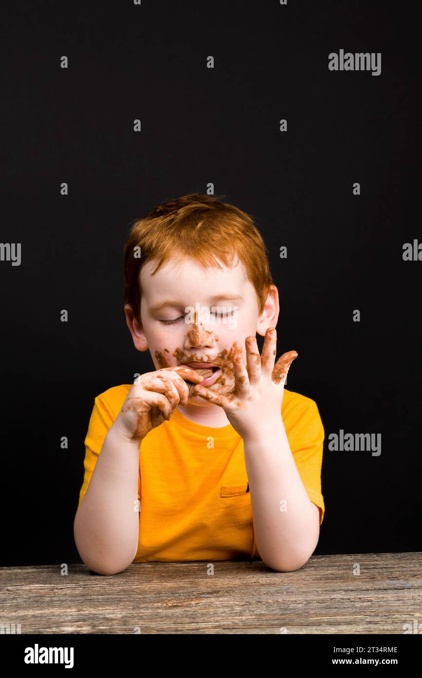 boy smeared in milk chocolate after nibbling and biting real cocoa ...