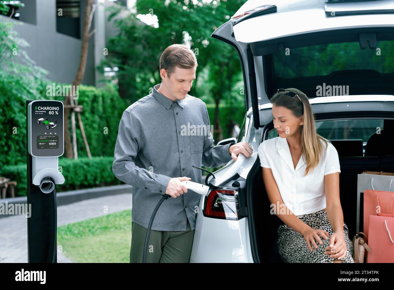 Young couple travel with EV electric car charging in green sustainable ...