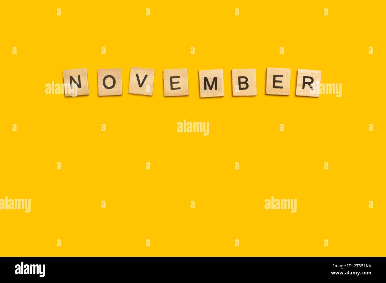 November word made with wooden letter blocks on a yellow background ...