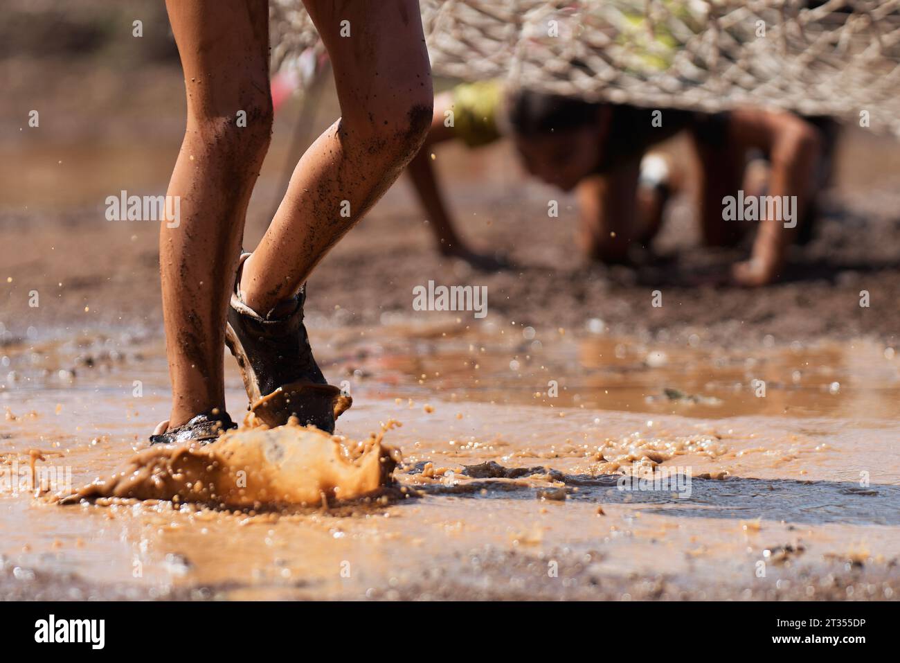 Mud race runners. Crawling, passing under a net obstacle during extreme ...
