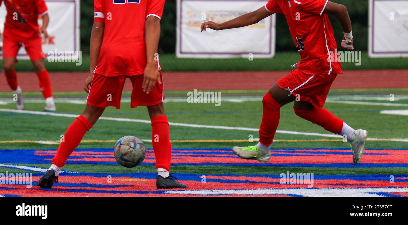 High school soccer players wearing red uniforms passing the ball to ...