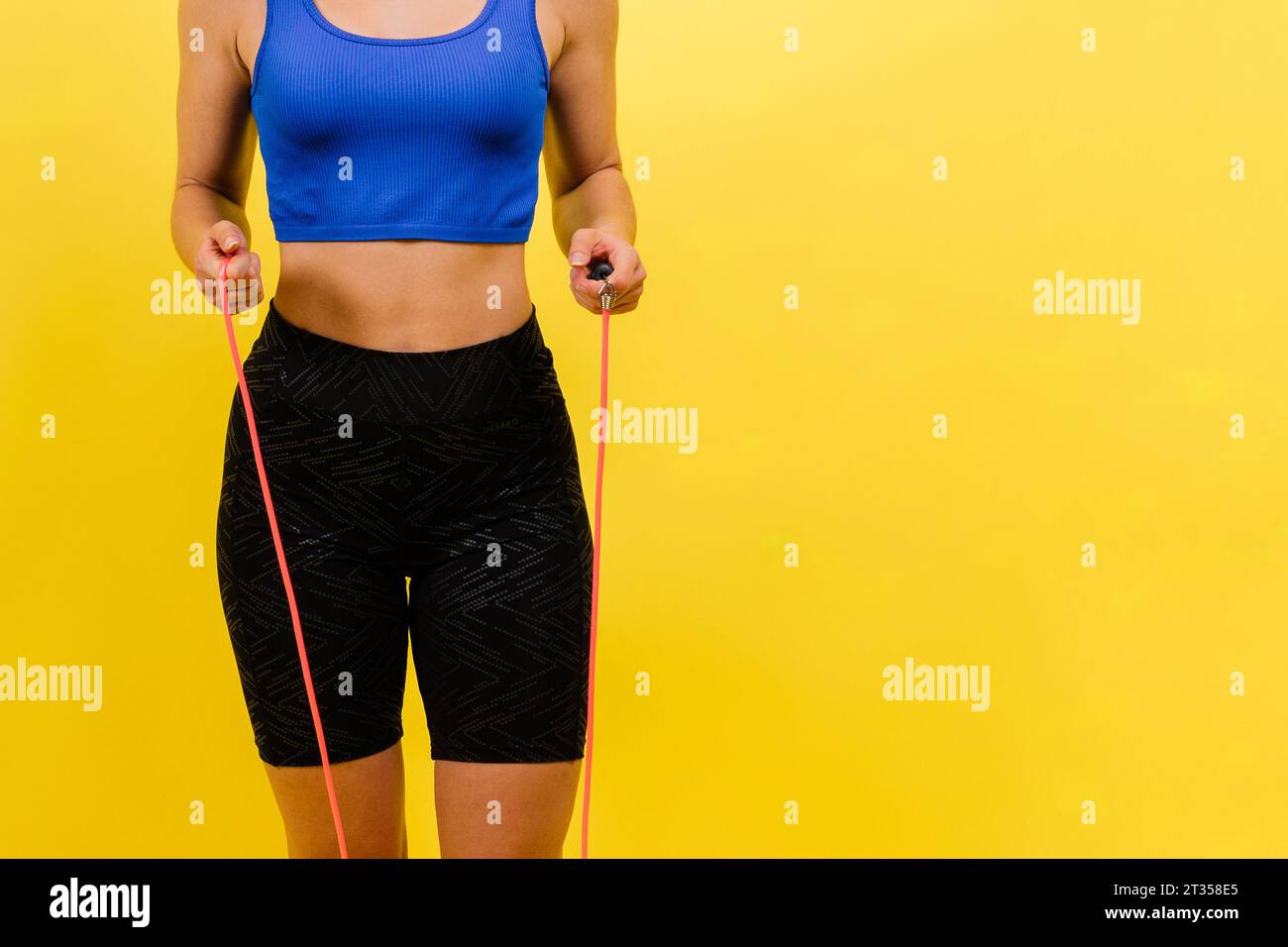 Fit female athlete with ponytail jumping with rope during fitness ...