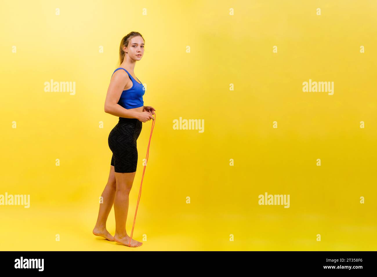 Fit female athlete with ponytail jumping with rope during fitness ...