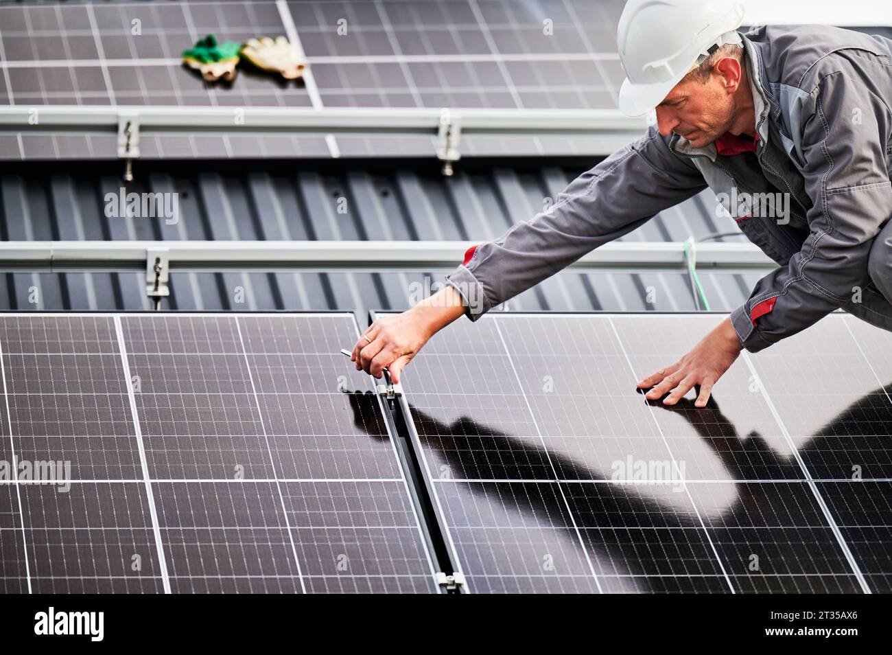 Man installer mounting photovoltaic solar panels on roof of house ...