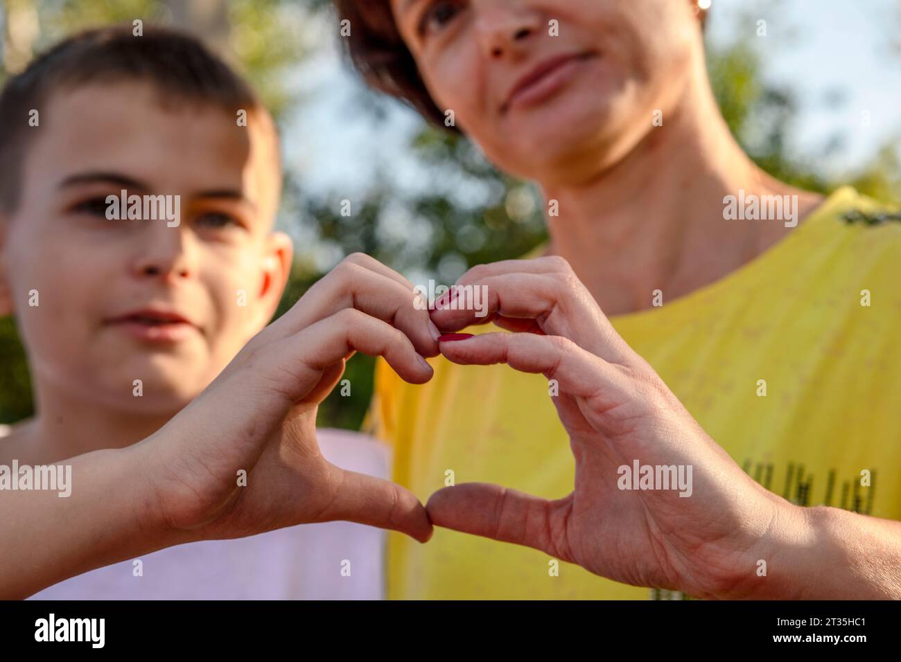 Mom and son making heart hand gesture together happy smiling look in ...